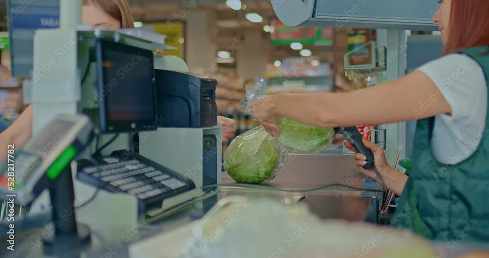 Female customer lays out products at the supermarket checkout. Cashier ...