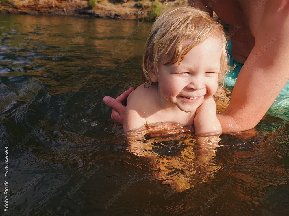 Father teaching a child to swim in the river. Baby swimming lessons on ...