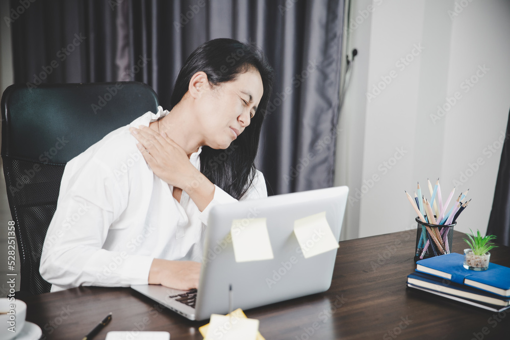 Young asian woman is sitting at work and has tension pain in her neck ...