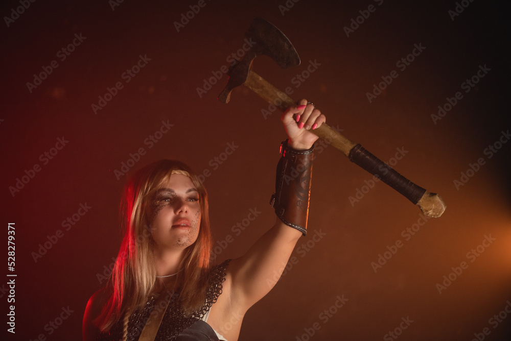 Warrior woman in the armor stands with the raised up axe. Victory ...
