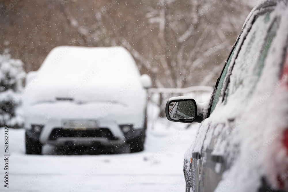 Heavy snowfall covered roads and cars. The car in the parking lot is ...