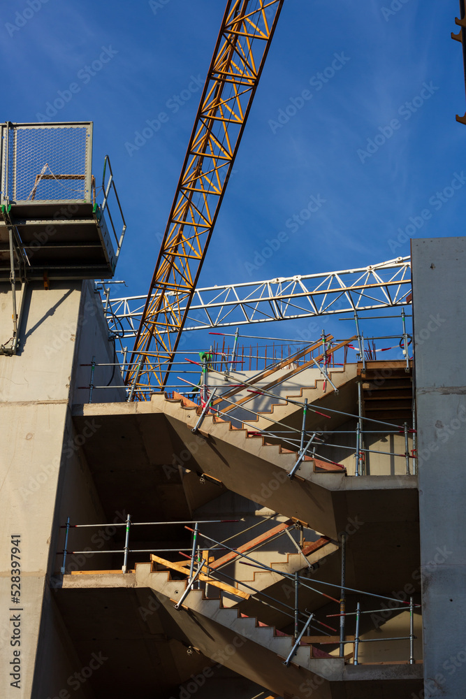 Construction site with scaffolding, concrete stairs, and sky cranes ...