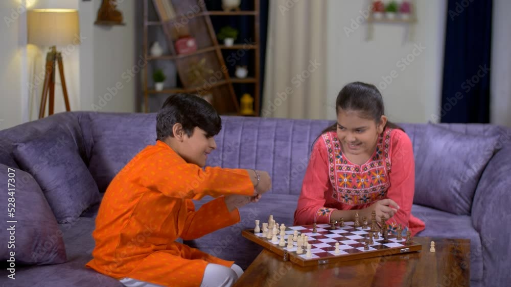 Young Indian siblings playing a board game together in the living room ...