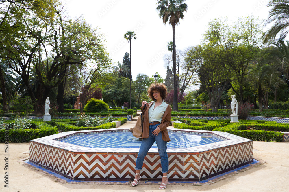 Beautiful woman with curly hair posing in front of a fountain in ...
