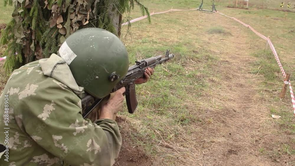 a soldier in a helmet from a prone position shoots at a target with a ...