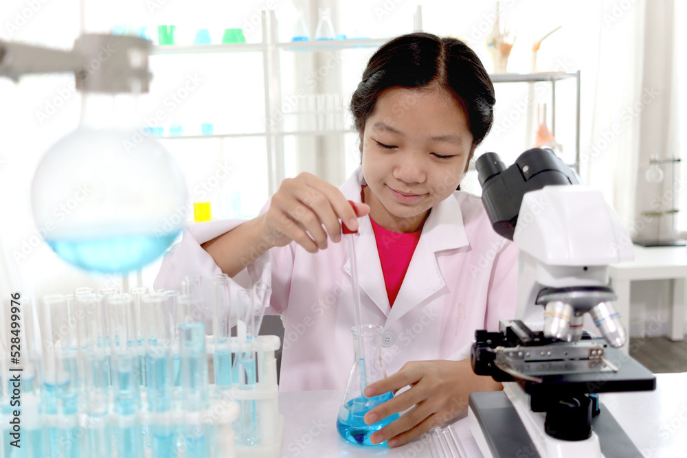 Foto de Adorable schoolgirl in lab coat doing science experiments ...