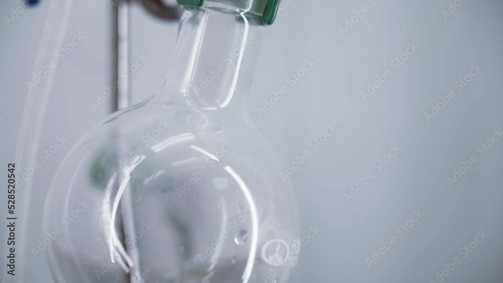 Drops slowly flow down the tube into the flask. Distillation process ...