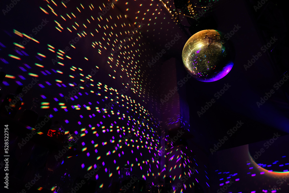 Poster A large disco ball reflects the light of yellow, and purple ...