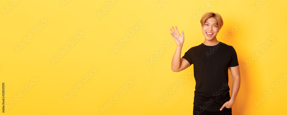 Portrait of handsome friendly asian guy in black outfit, waving hand to ...