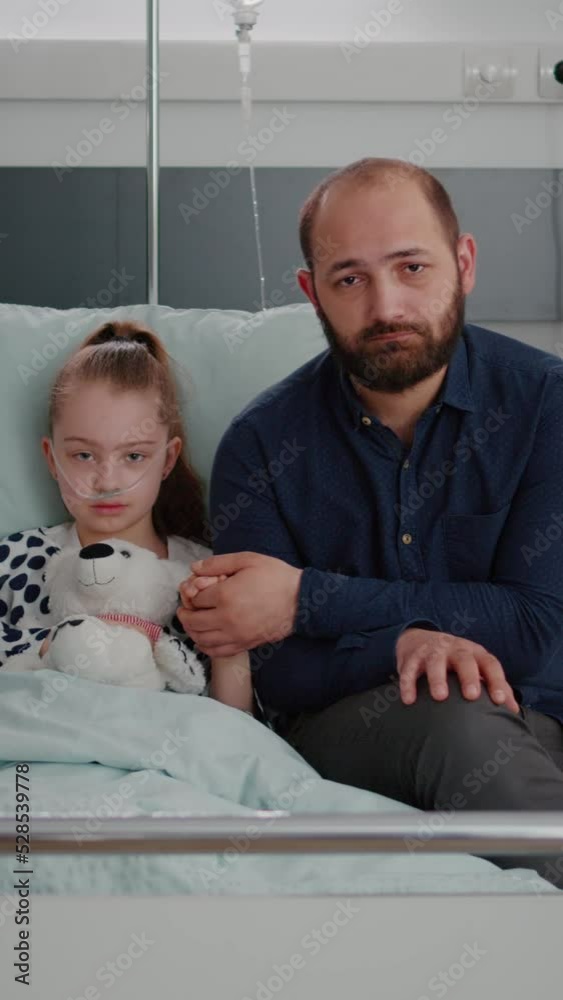 vertical video: Portrait of sad father holding sick child hands looking ...