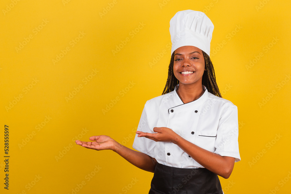 Young afro-brazilian woman, chef, presenting something to the left ...