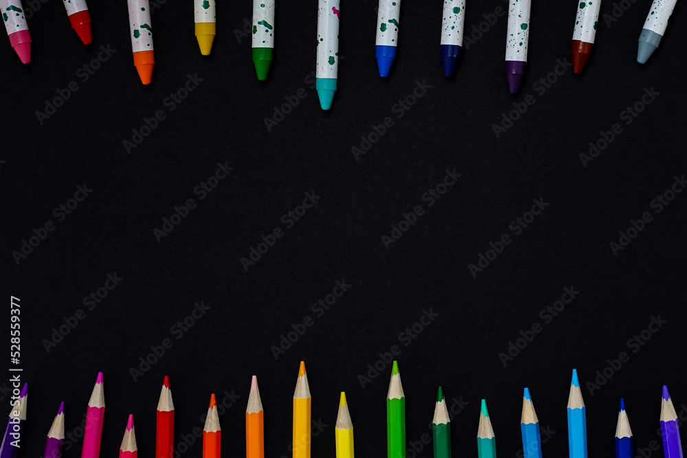 Frame of colored pencils and wax crayons, black background with space ...
