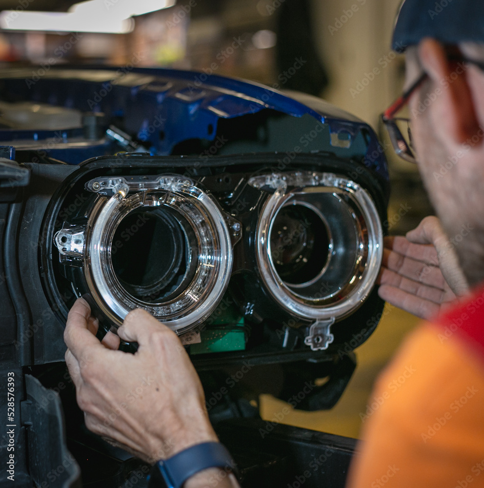 Car headlight in repair close-up. The car mechanic installs the lens in ...