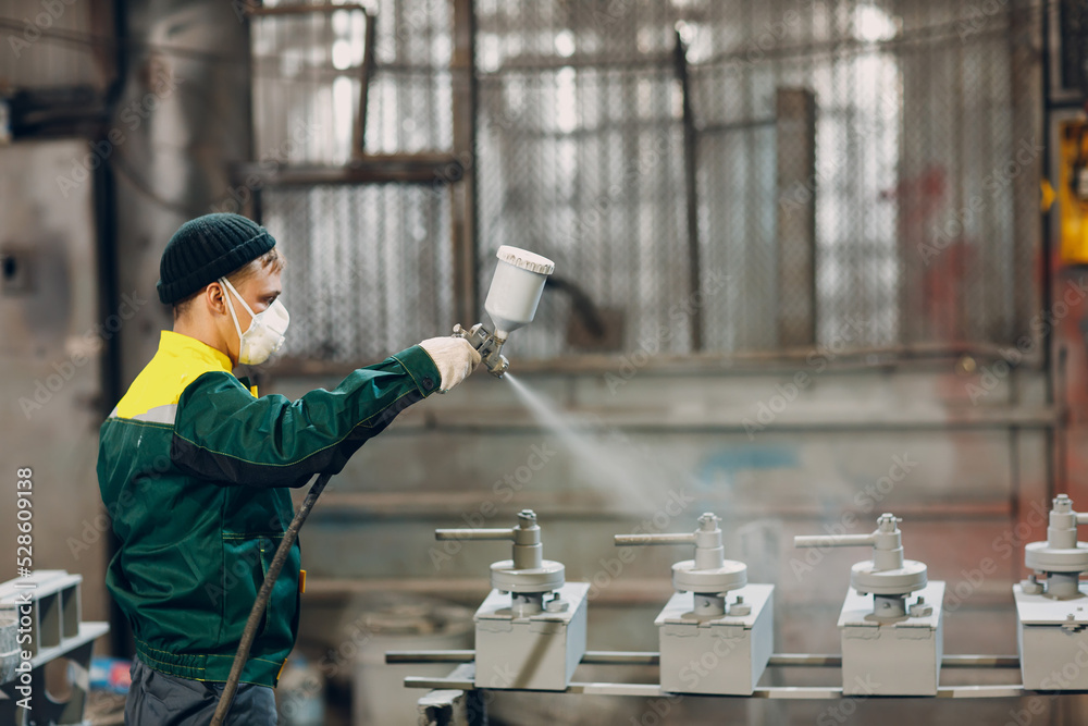 Powder primer coating of metal parts. Worker man in a protective suit ...