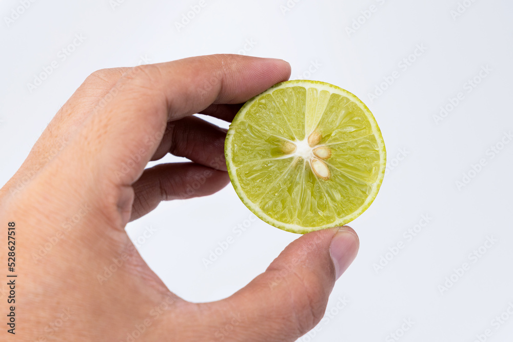 Hand holding lime sliced isolated in white background. Fresh lemon sour ...