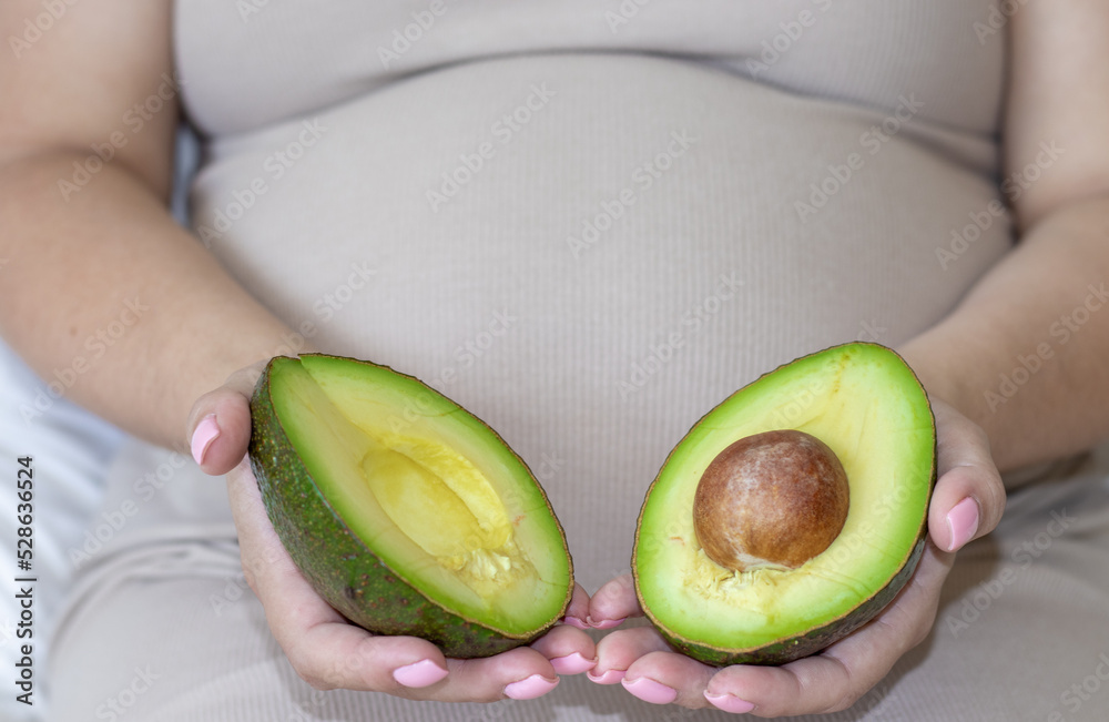 pregnant woman lies on bed holding avocado with bone.proper nutrition ...