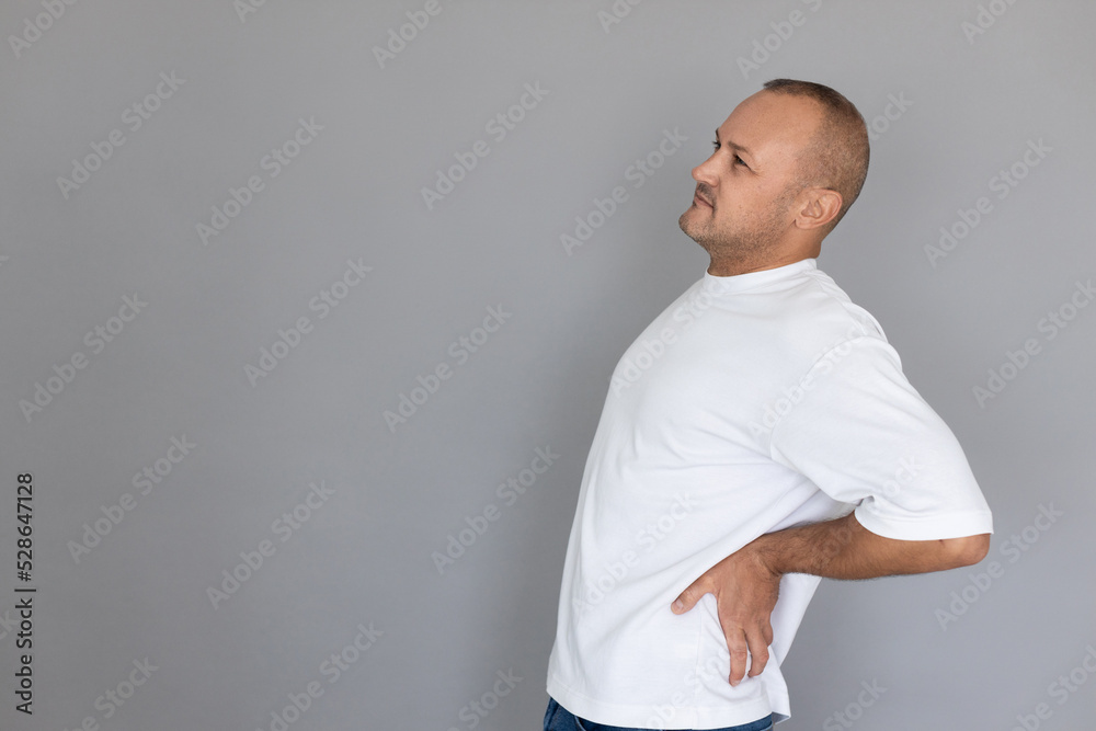 Portrait of mature Caucasian man touching aching low back. Balding guy ...