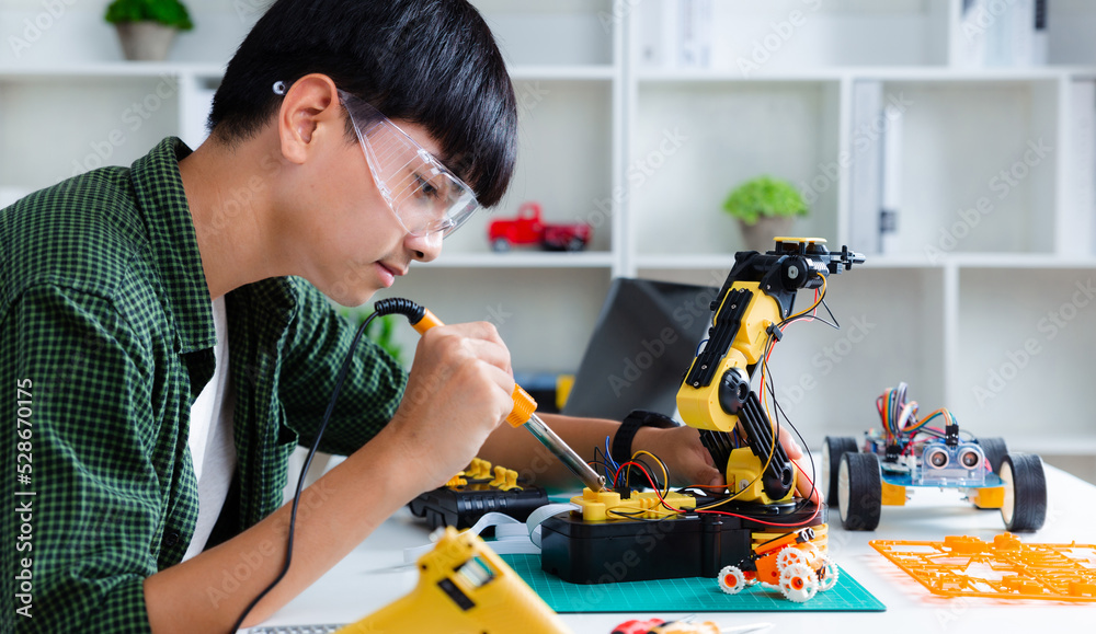Asian teenager doing robot arm homework project in house, technology of ...