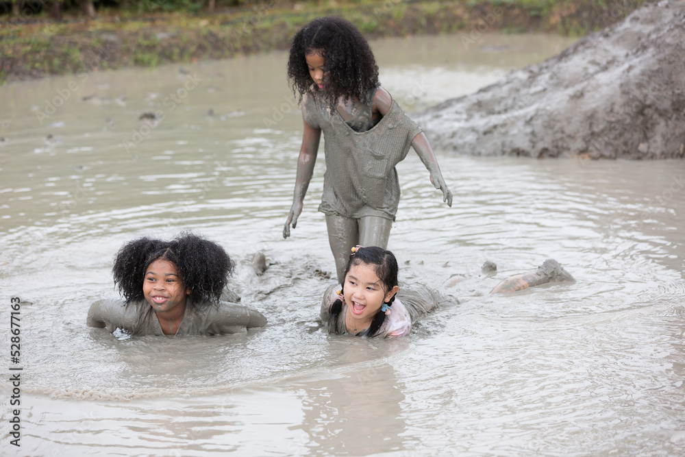 Group of happy children girl laying and playing in wet mud puddle on ...