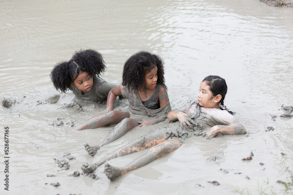 Group of happy children girl laying and playing in wet mud puddle on ...