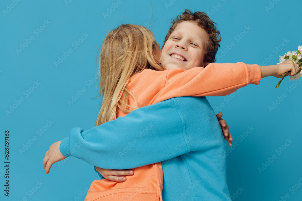 children stand on blue background in bright clothes and happily hug ...