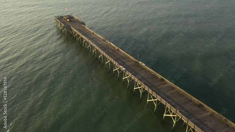 Fishing pier in early morning sun at coastal vacation destination ...