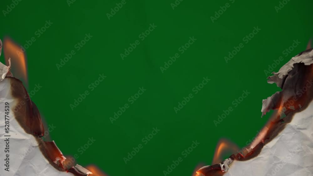 White paper burns from below on a green background copy space. The ...