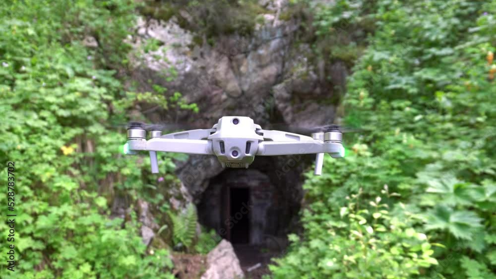 The DJI Air2S quadcopter hovers in front of cave entrance. There are ...