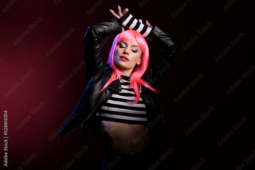 Trendy female rocker with natural leather jacket and pink wig psoing in ...