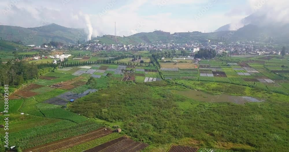 Backward Drone shot of rural landscape of Dieng Plateau with view of ...