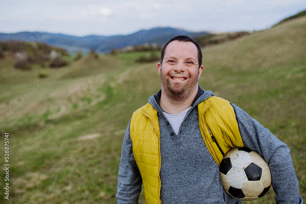 Happy young man with Down syndrome playing with soccer ball in nature ...