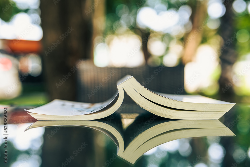 Opened book upside down on the glass table in the garden Stock Photo ...