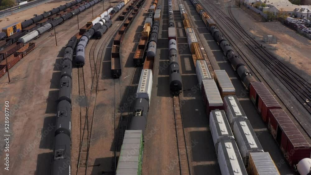 Low tilting up aerial shot of rows of freight trains in an industrial ...