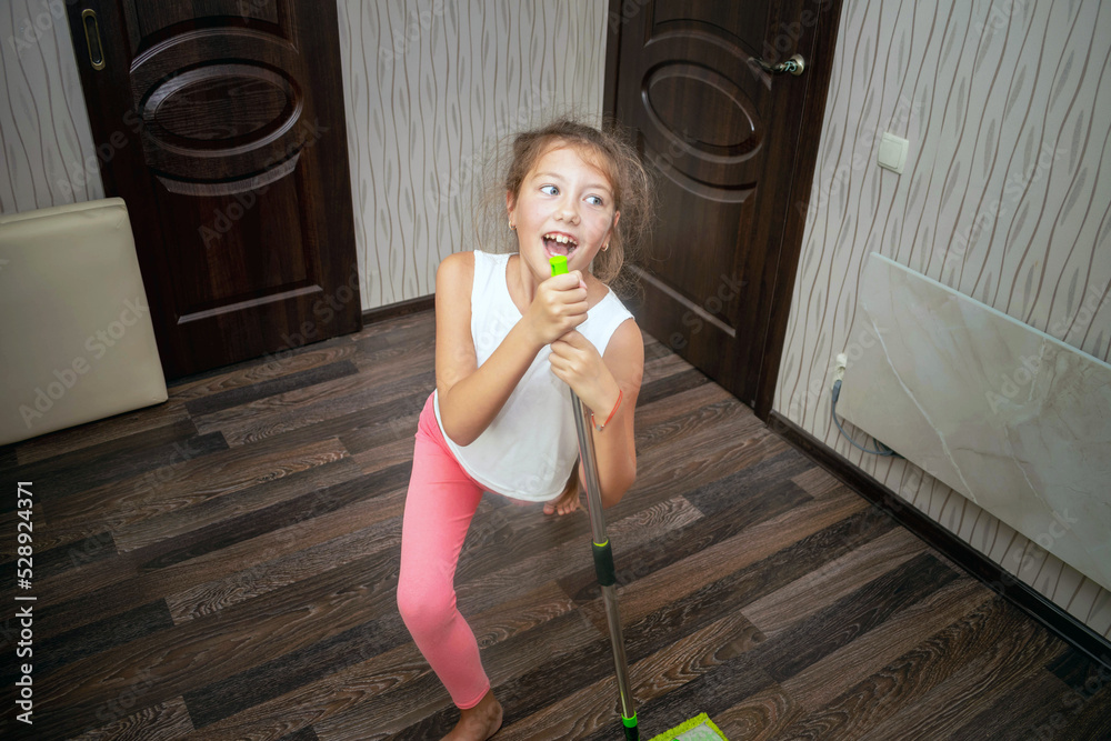 The girl sings into the handles of the mop as if into a microphone. The ...