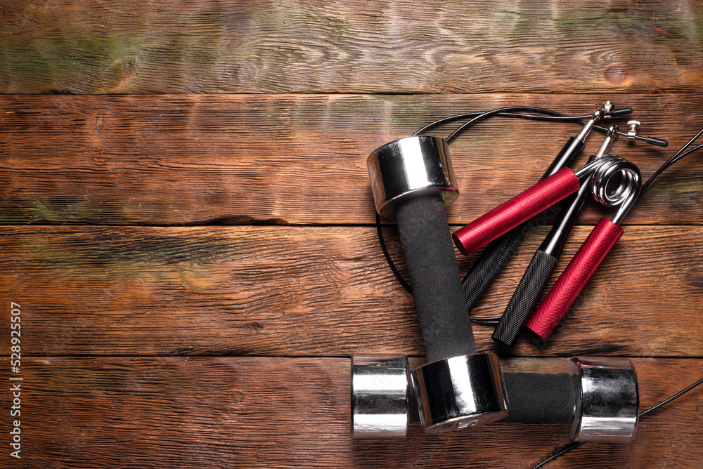 Small dumbbell, skipping rope and carpal expander on the wooden floor ...