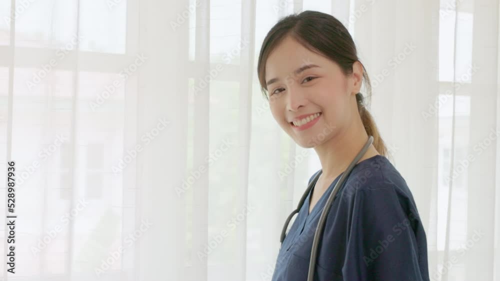 Looking at the camera is a happy young Asian woman doctor wearing a ...