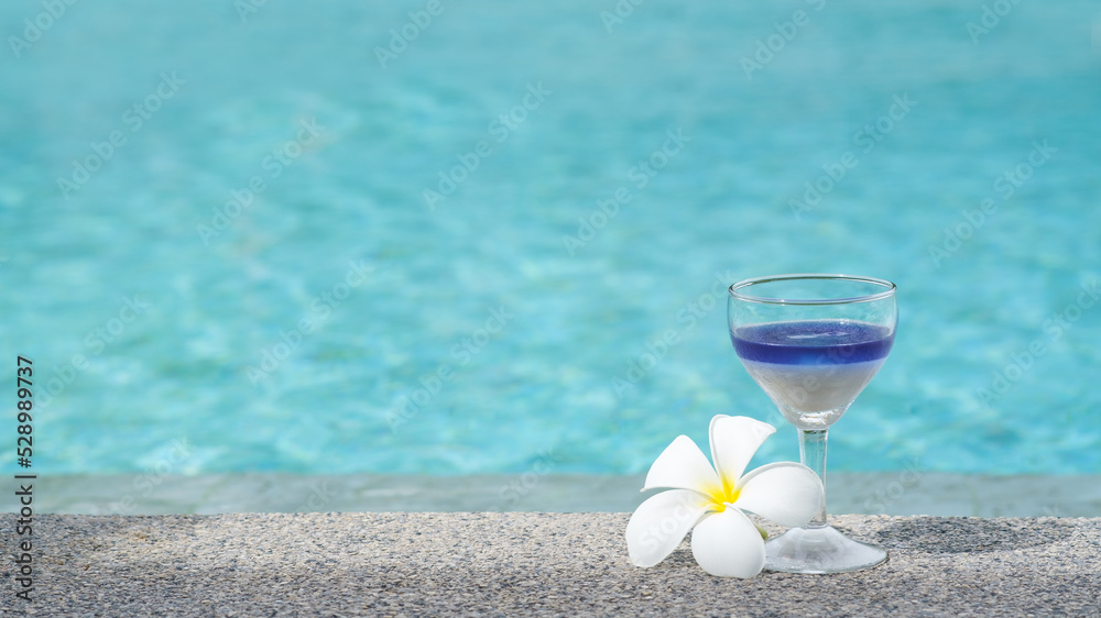 Glass of welcome drink at infinity swimming pool with ocean background ...