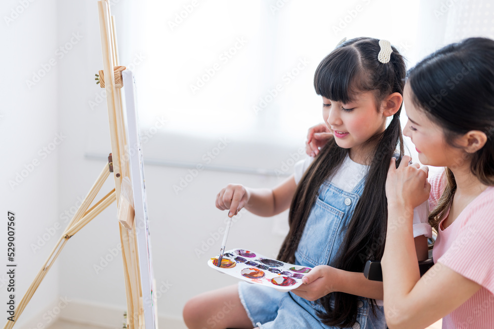 Asian female teacher and little girl having fun painting during art ...