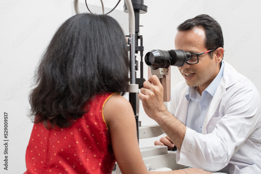 Foto de Indian optometrist doing eye test with slit lamp in modern ...