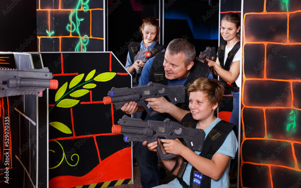 Modern young father and teen son with a laser pistols playing laser tag ...