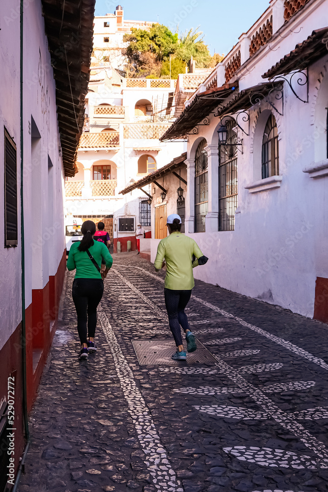 Two people running in a street of a magical town in Taxco Mexico Stock ...