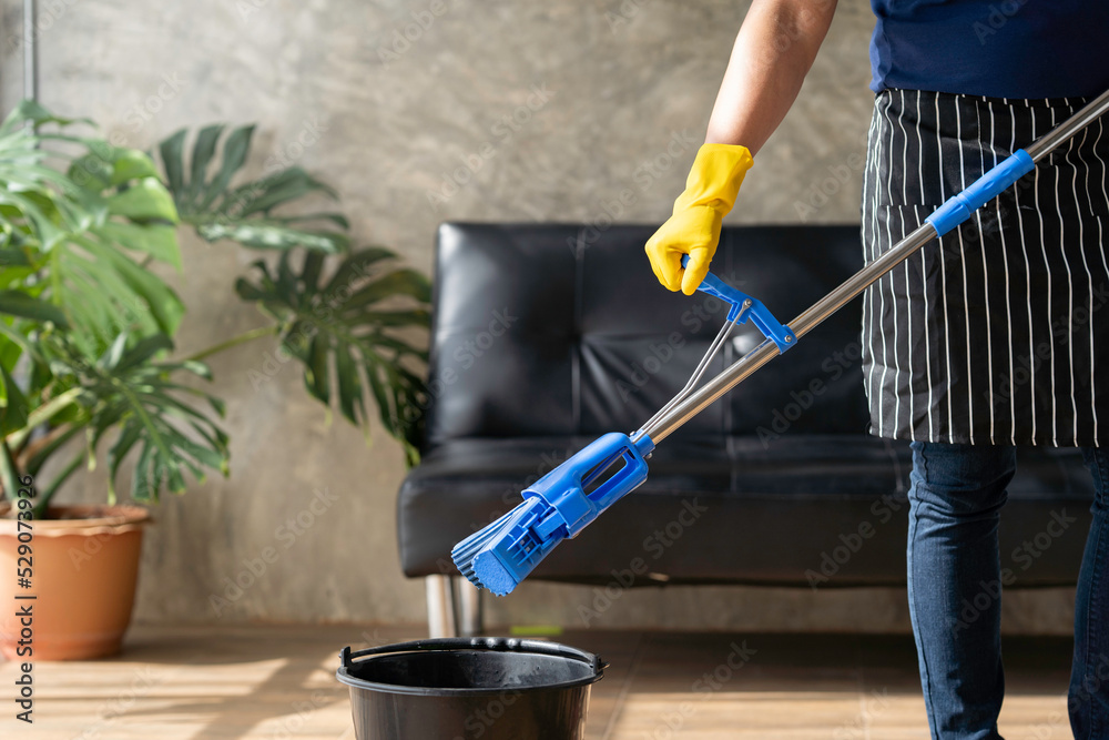 A young butler cleans the floor, mops the floor, carries a mop and a ...