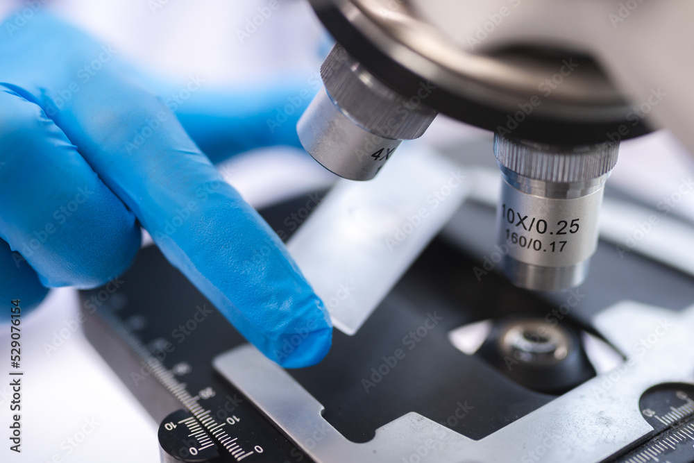 Scientist analyzing microscope slide at laboratory. Young woman ...