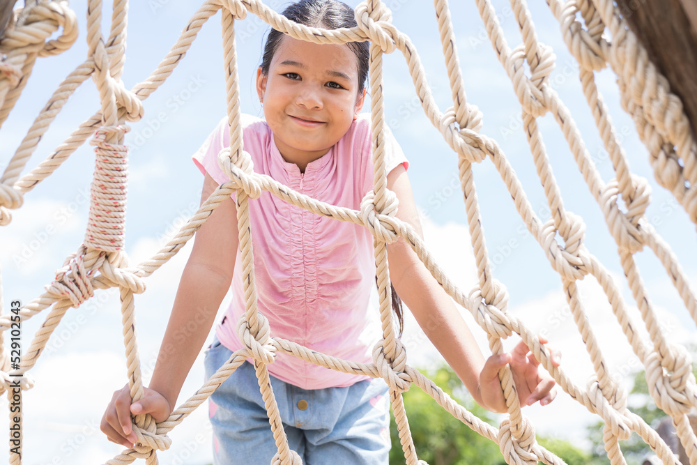 Teenage girl playing on rope wall at the playground. Asian child girl ...