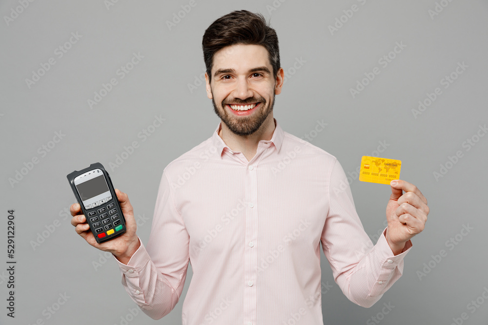 Young caucasian man 20s he wear basic white shirt hold wireless modern bank payment terminal to ...