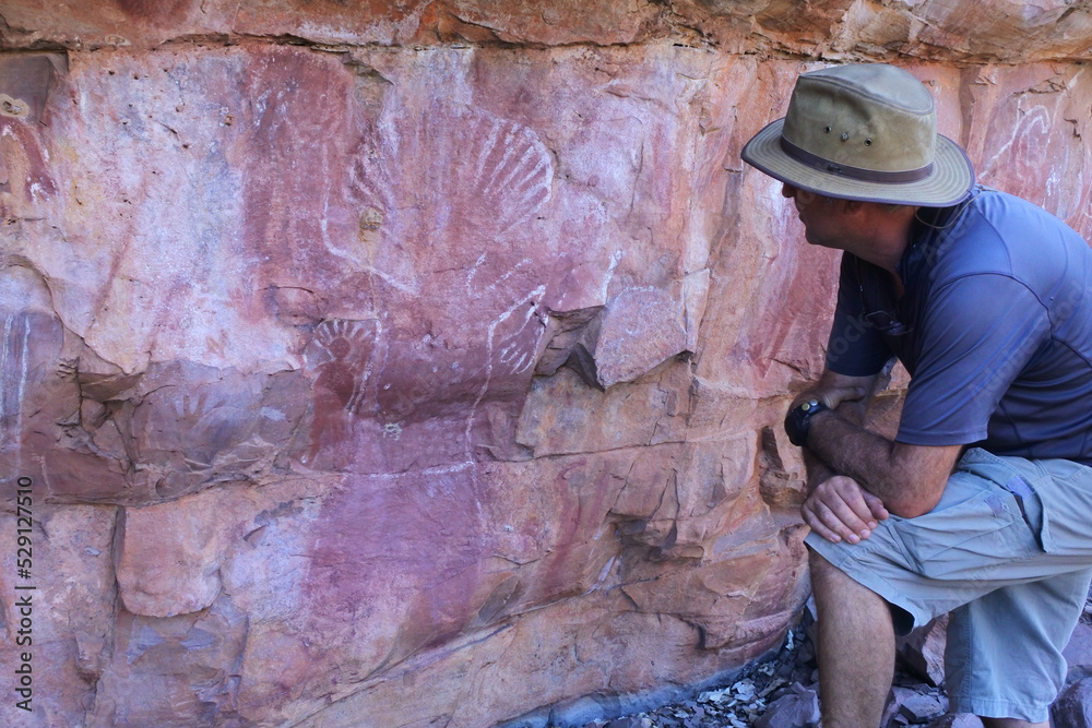 Australian man looking at Australian Aboriginal mythology rock ...