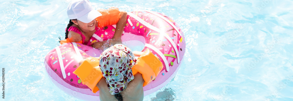 two girls splash in an outdoors swimming pool in summer. Happy children ...