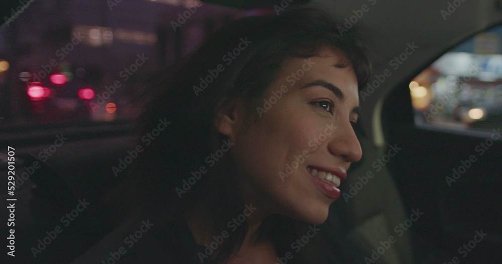 Happy female passenger in backseat of car smiling while looking out ...