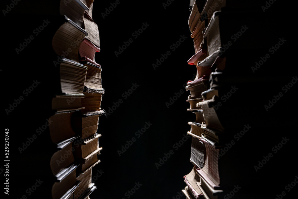 Two rows of old books in the dark on a black isolated studio background ...