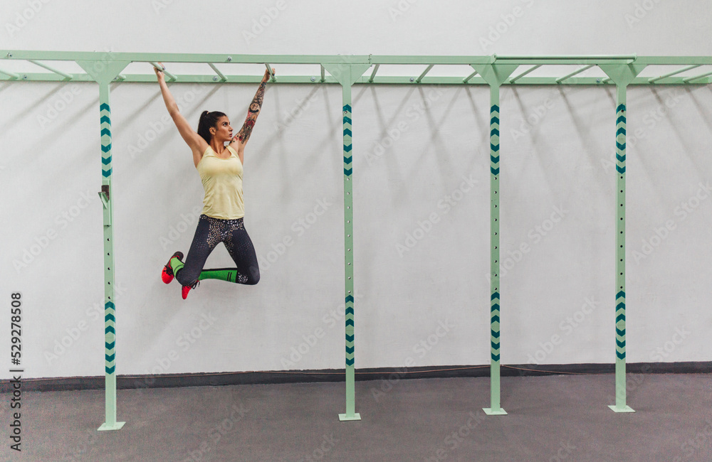 Athlete hanging on monkey bars in gym Stock Photo | Adobe Stock